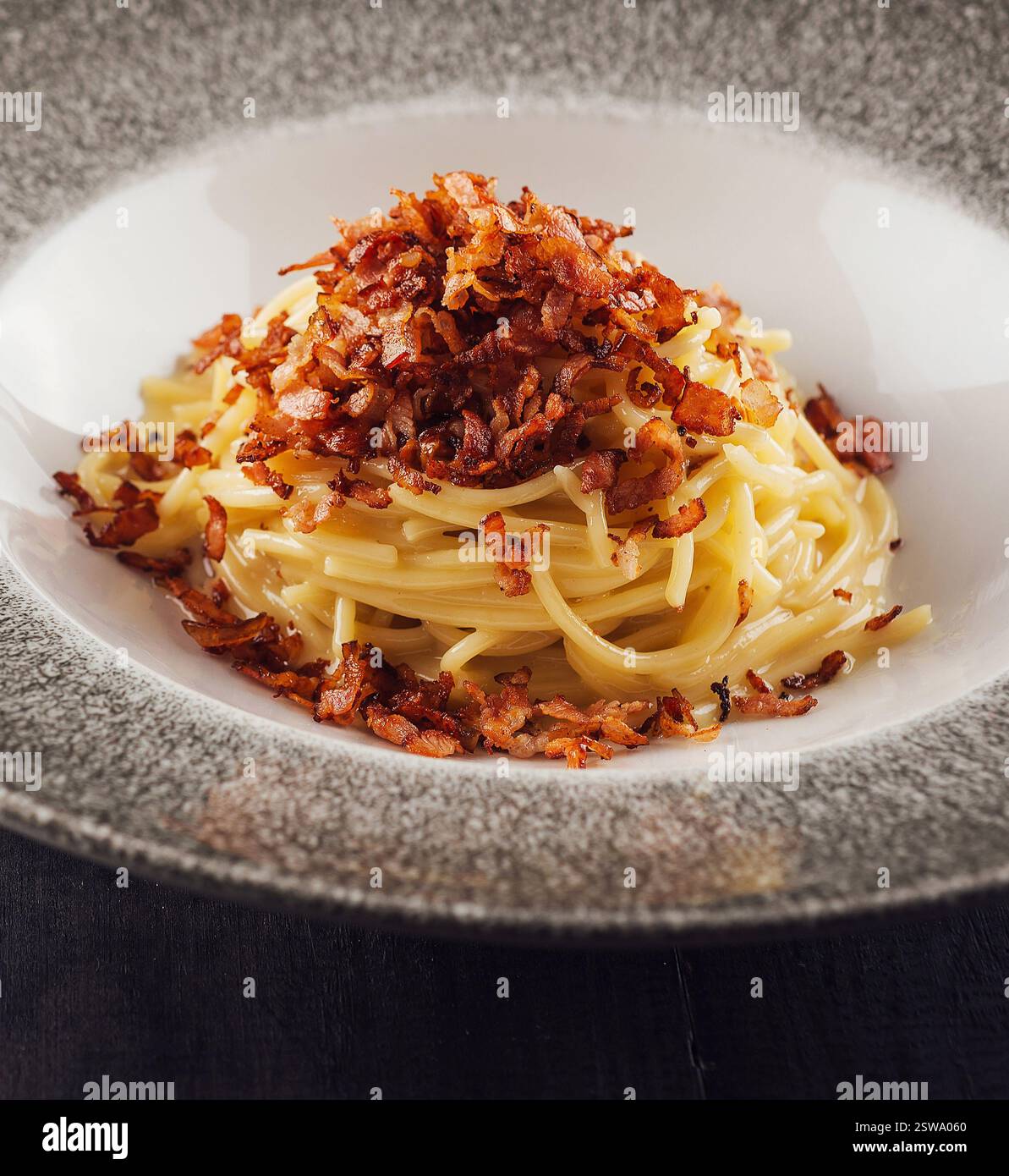 Delicious spaghetti carbonara topped with crispy bacon bits, served on ...