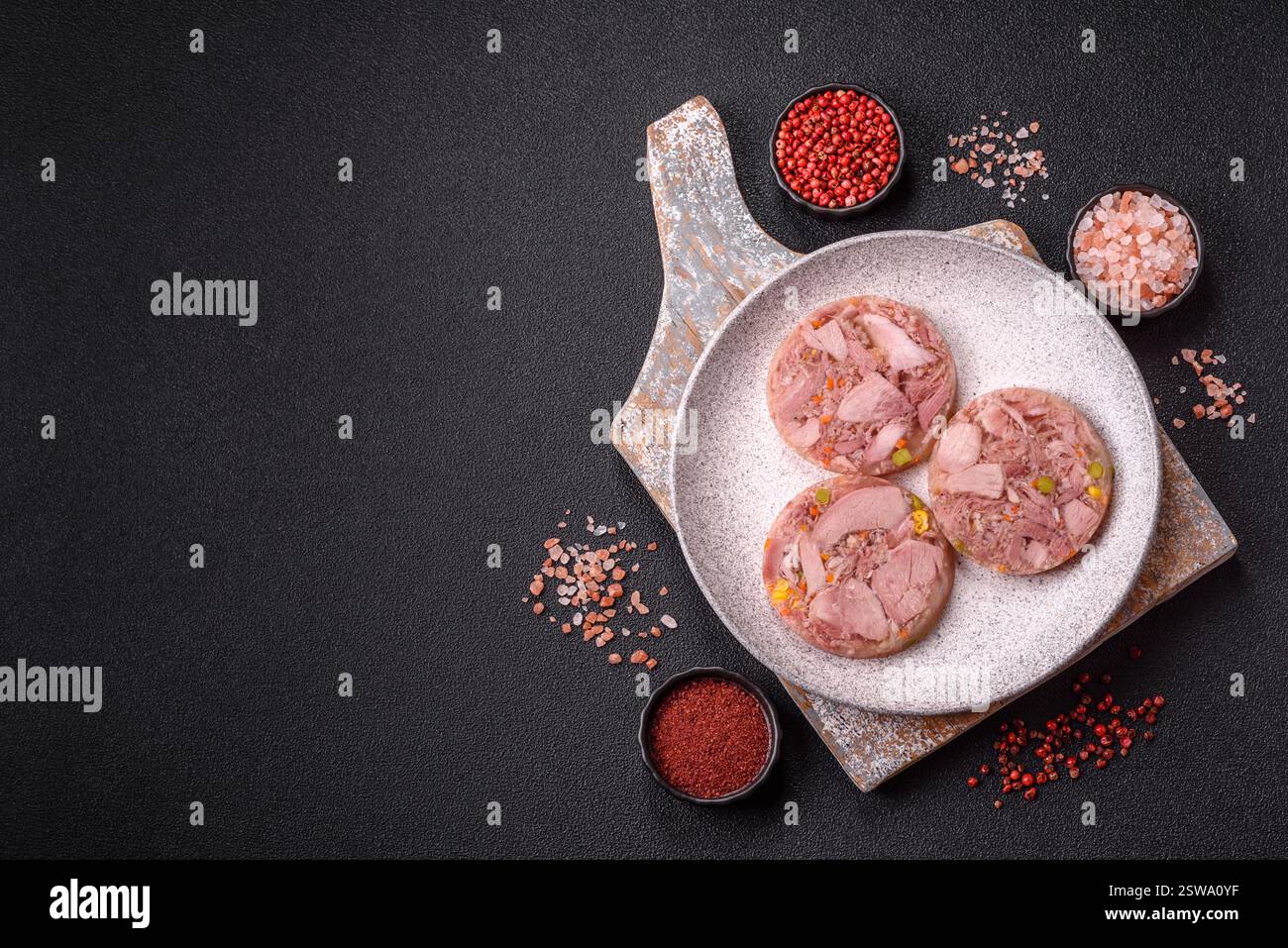 Homemade brawn with salt, spices, herbs and vegetables on a dark ...