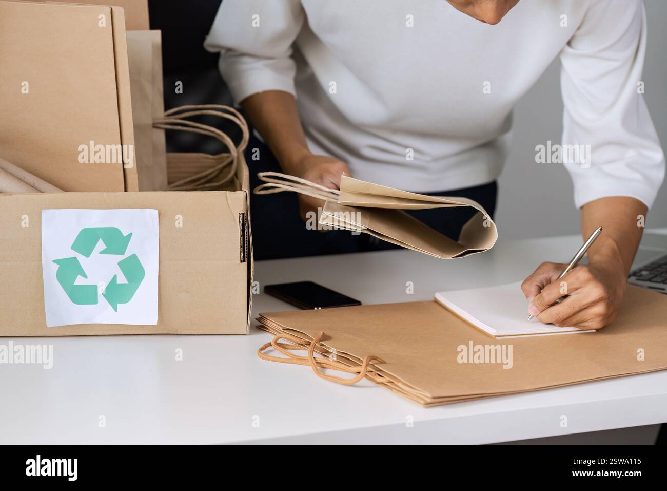 Individual organizing recycled paper bags and taking notes in a ...