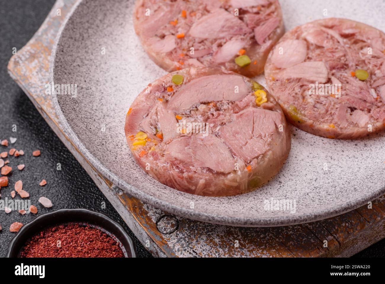 Homemade brawn with salt, spices, herbs and vegetables on a dark ...