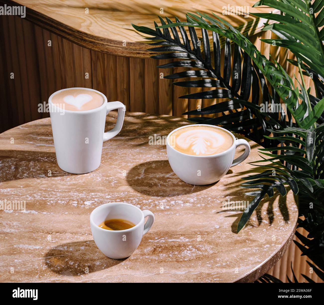 Three cups of coffee sitting on a table with a palm tree in the ...