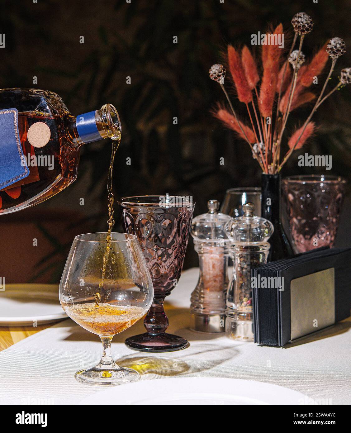 Bartender pouring alcoholic drink into glass at restaurant table Stock Photo - Alamy