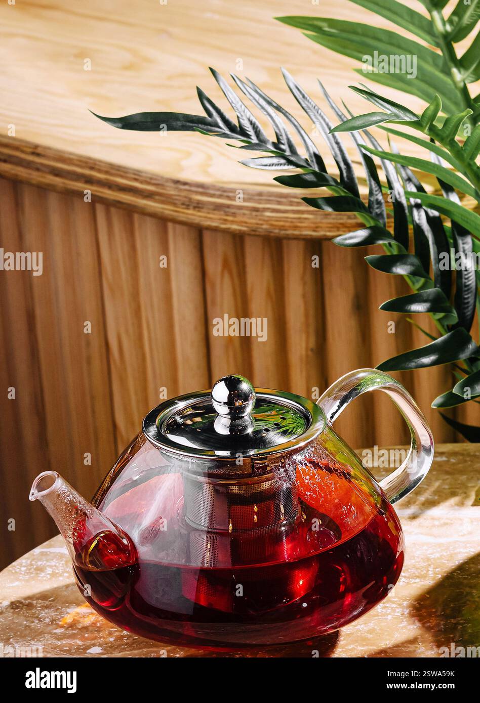 Glass teapot full of fruit tea with strainer sitting on table Stock ...