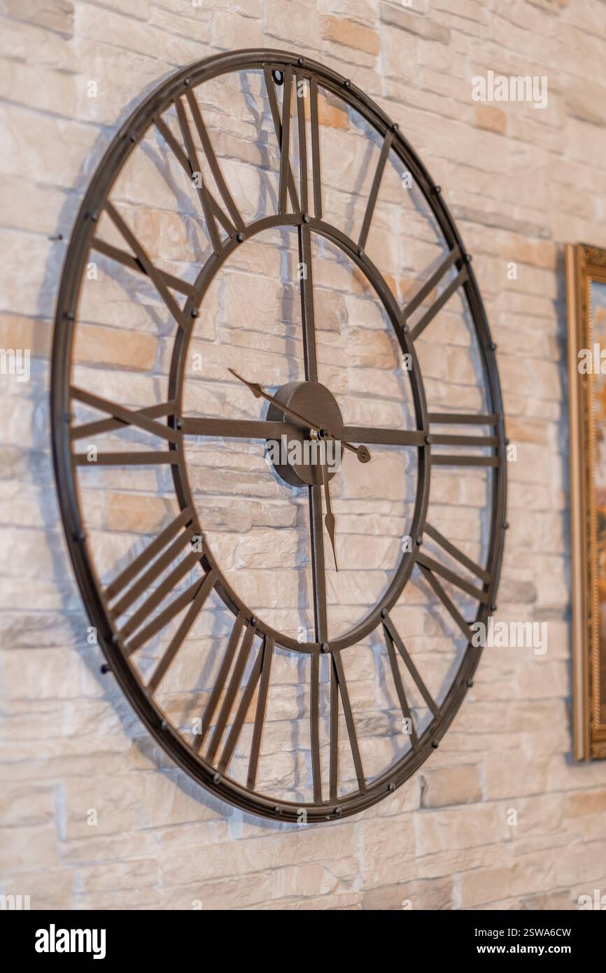 Large wall clock with Roman numerals against a textured stone ...