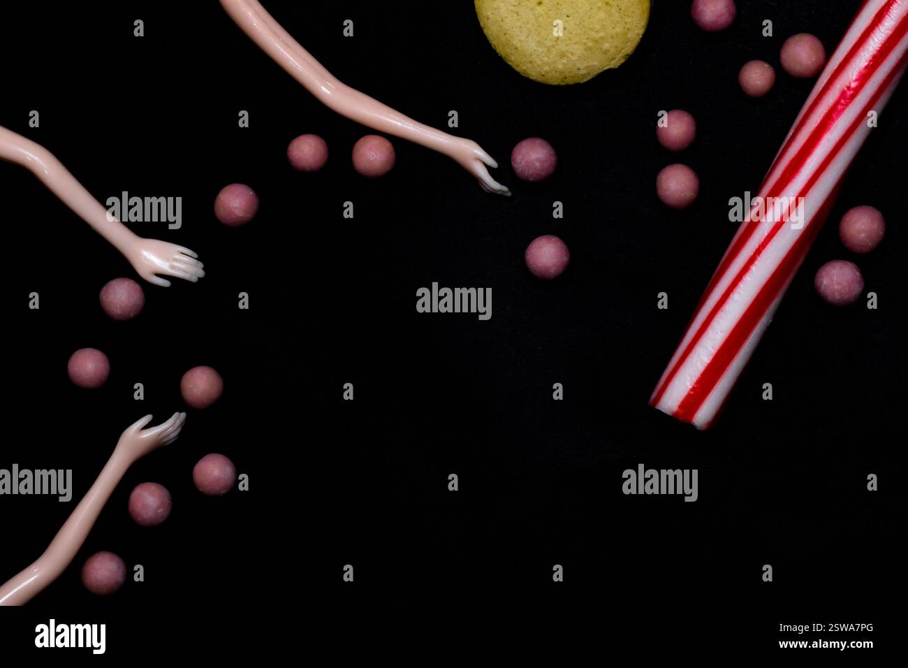 Plastic hands reaching to various candies and sweets isolated on black ...