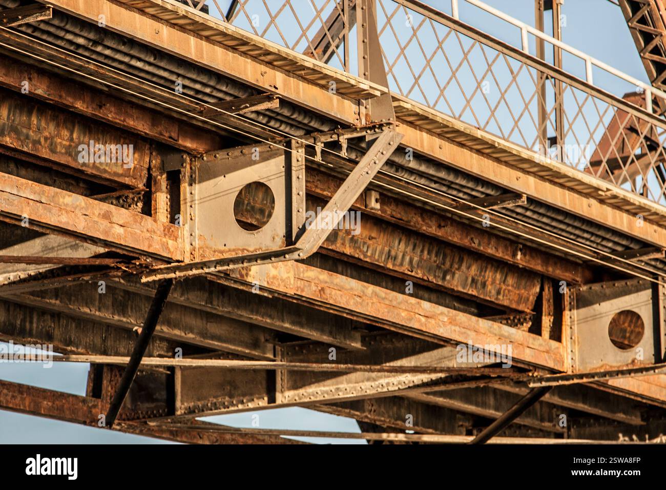 Bridge with rusted metal beams and a metal fence. The bridge is old and ...