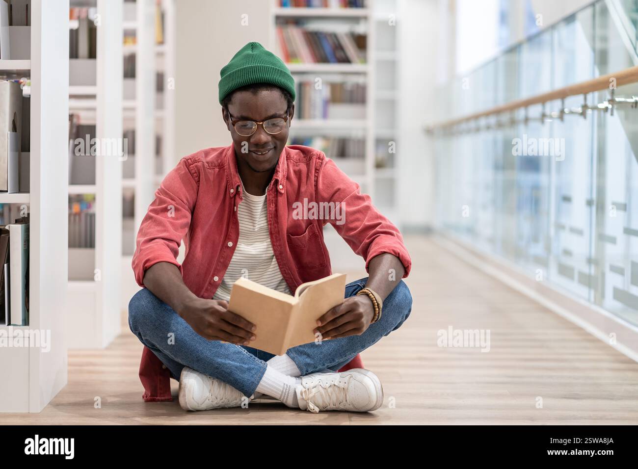 Interested Black student man sitting on floor in library. Focused ...