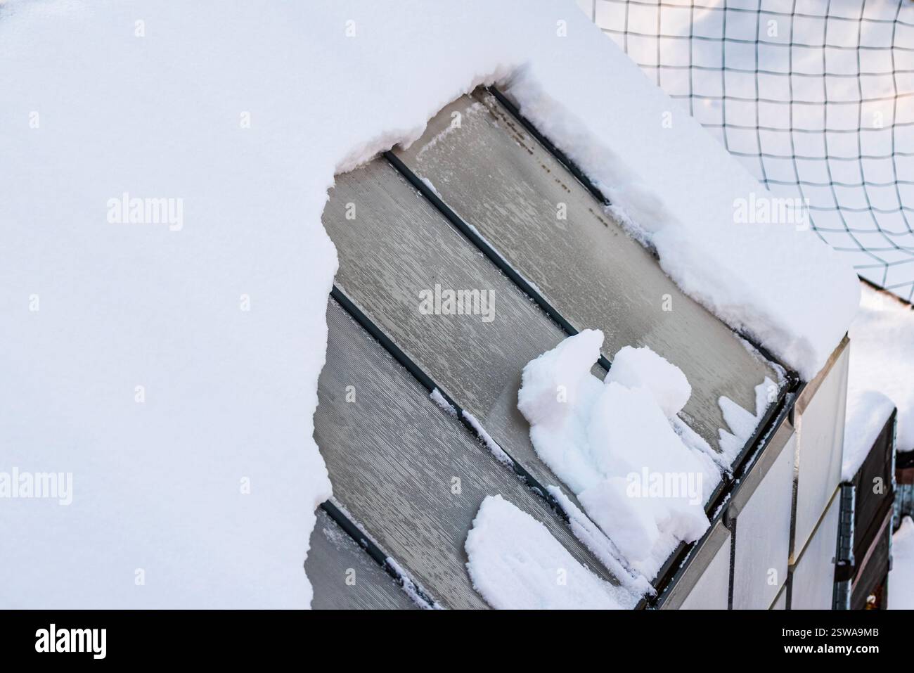 Snow-covered greenhouse roof with partially melted snow revealing ...