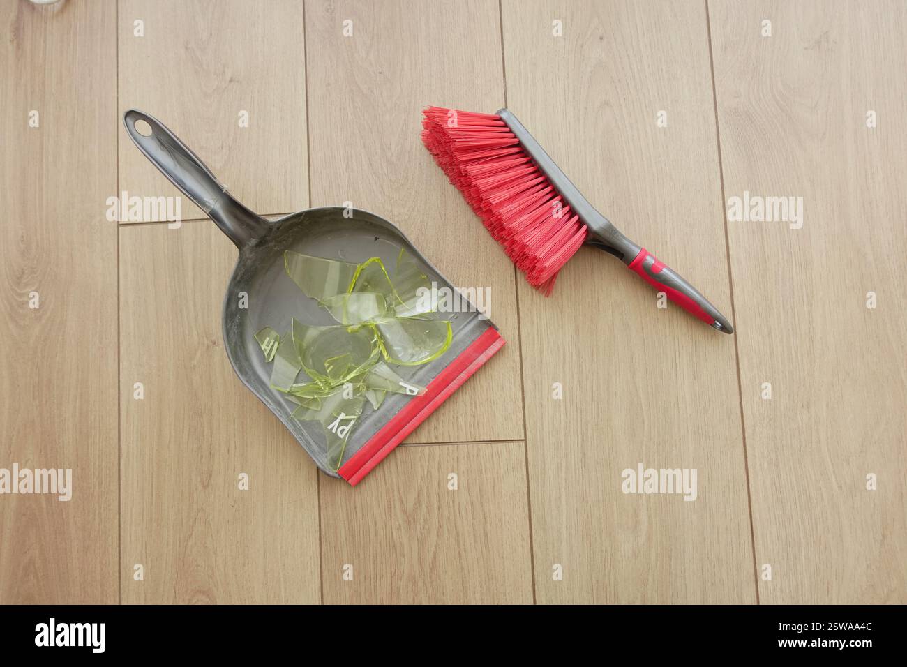 Cleaning up broken glass on wooden floor with a dustpan and brush Stock ...