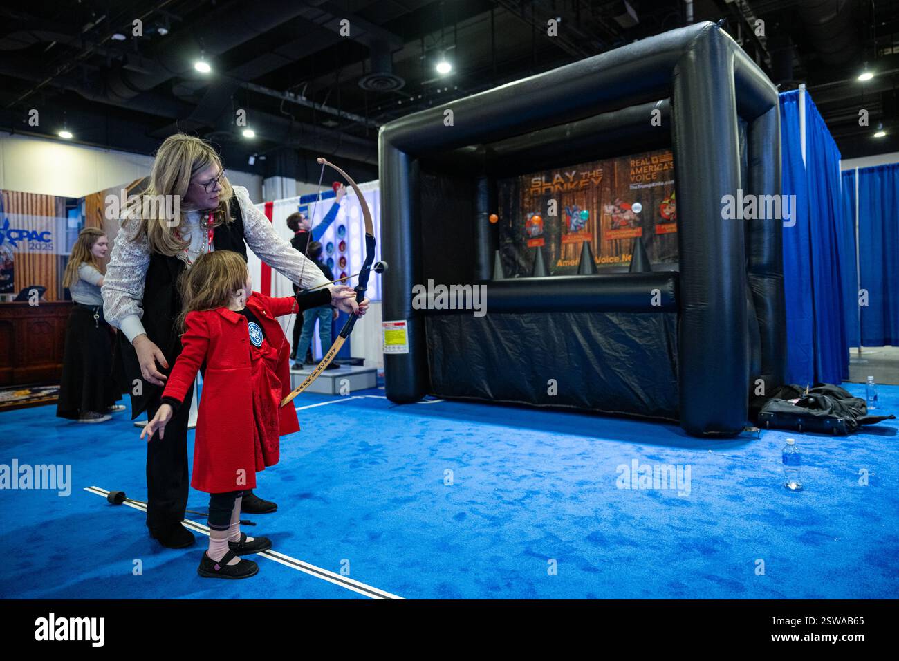 A girl shoots toy arrows at balloons at the 2025 Conservative Political ...