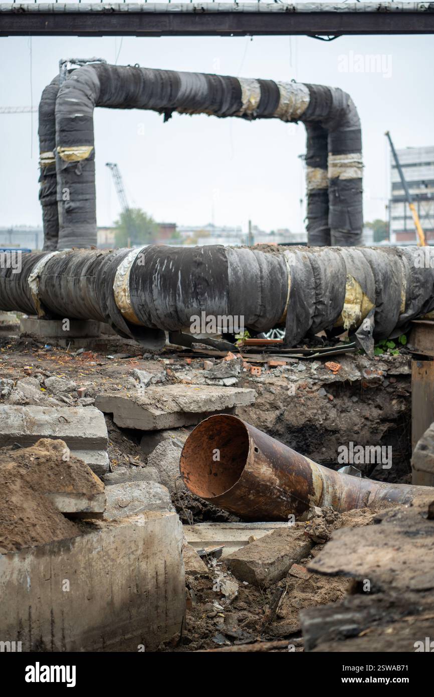 Scattered fragments of water, gas pipes in excavated trench. Worn pipe ...