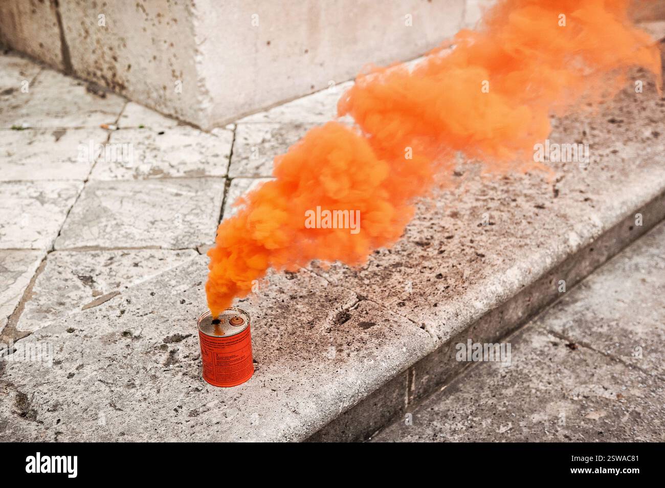 Orange smoke can on stony ground Stock Photo - Alamy