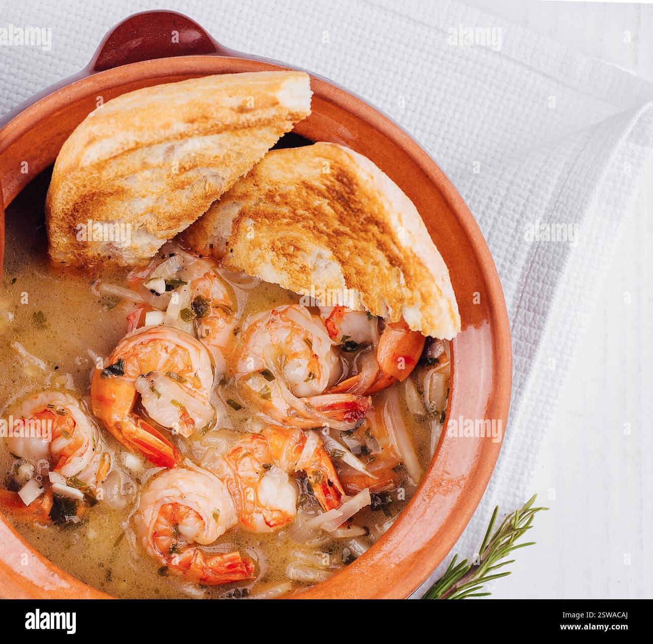 Creamy shrimp stew served in a terracotta bowl with toasted bread and ...
