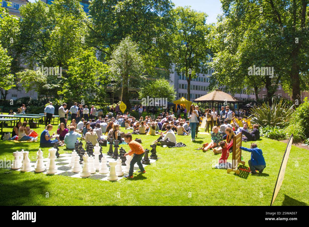 Picnic and games in Portman Square Garden, London. Many people enjoying ...