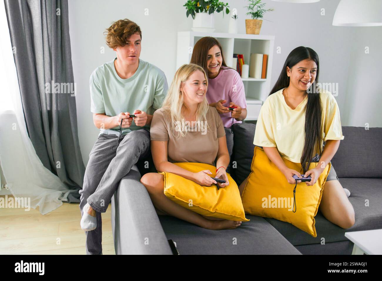 Cheerful group of friends playing video games together at home, leisure ...
