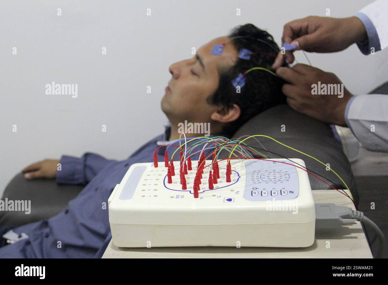 Electroencephalogram EEG in adult Latino man with wires in his head ...