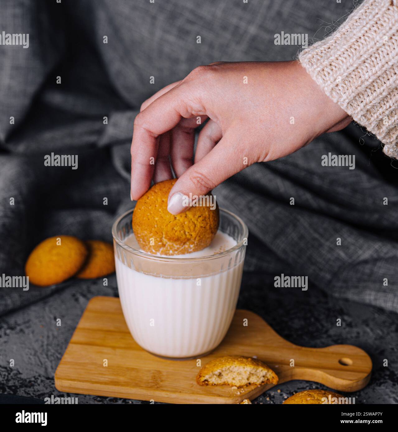 Dipping a cookie into a glass of milk Stock Photo - Alamy