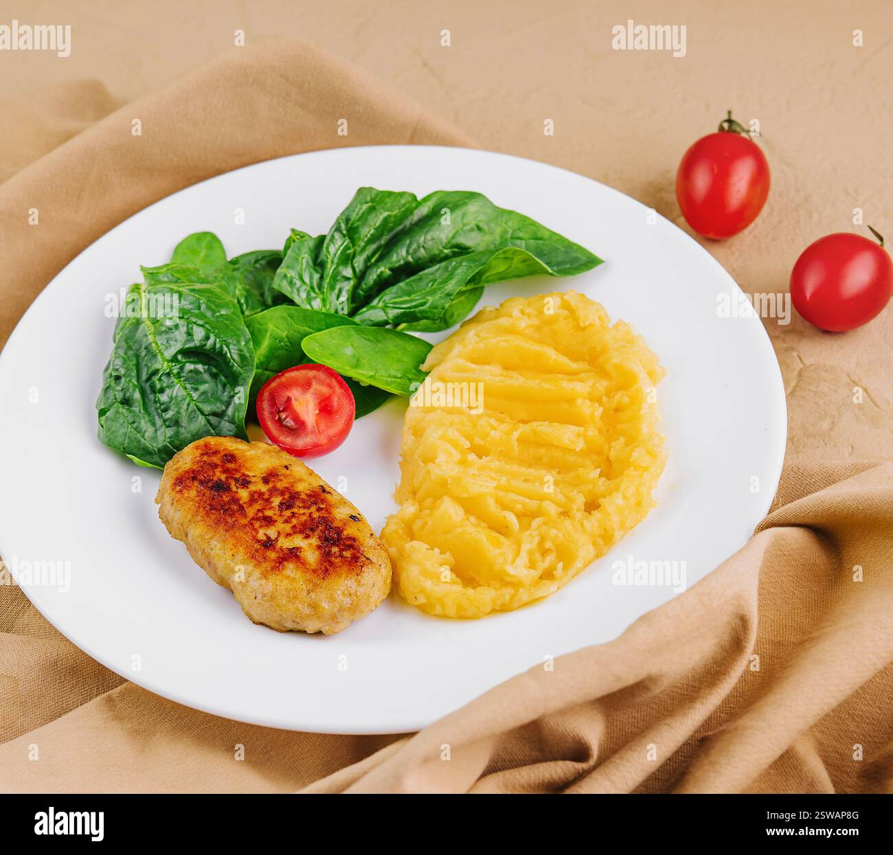 White plate showing chicken kiev with mashed potatoes and spinach being ...