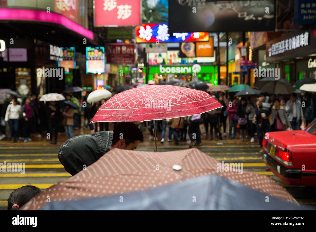 Pedestrians use umbrellas in the rain on a busy street in Hong Kong ...