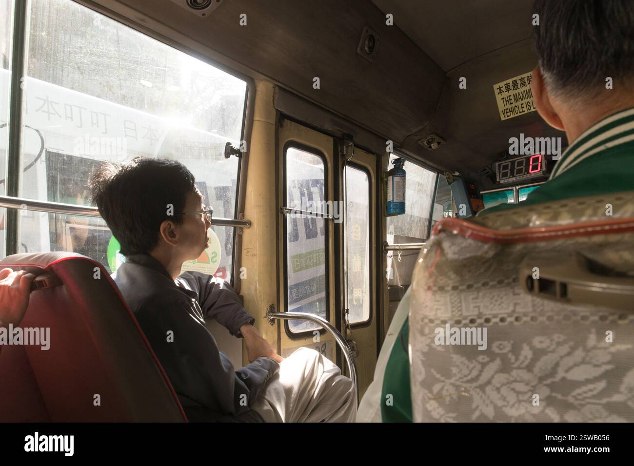 Passengers on a bus in Japan, likely in Tokyo, ride the MAXIMI vehicle ...