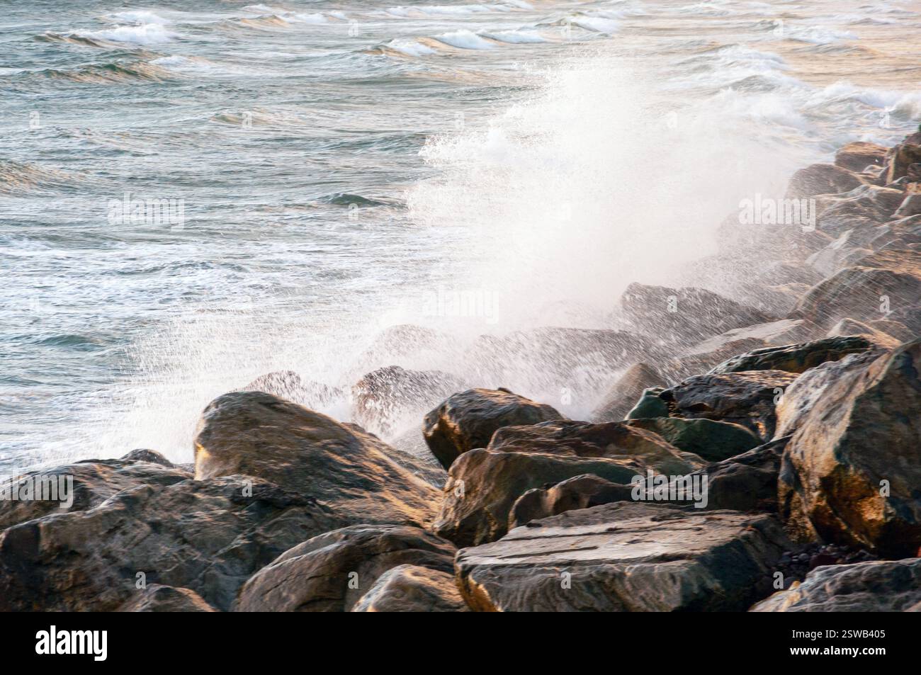 The ocean waves crash against the rocks, creating a powerful and ...