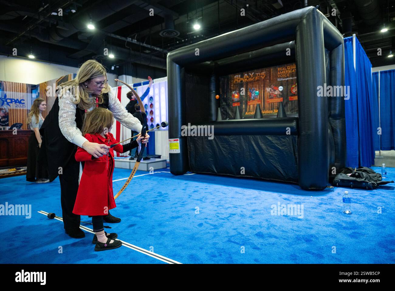 A girl shoots toy arrows at balloons at the 2025 Conservative Political ...