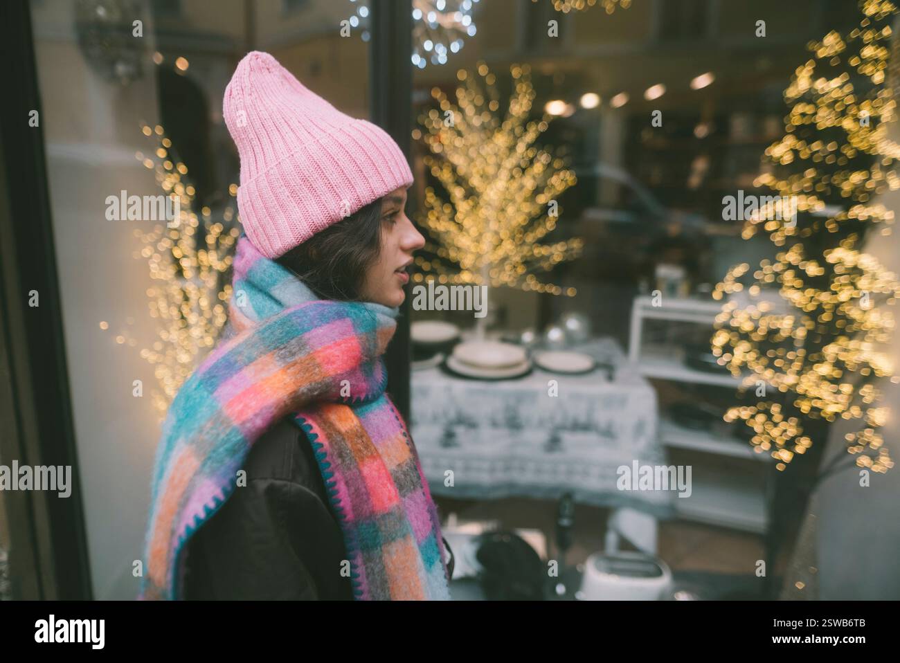 A woman adorned with a stylish pink hat and a matching scarf is ...