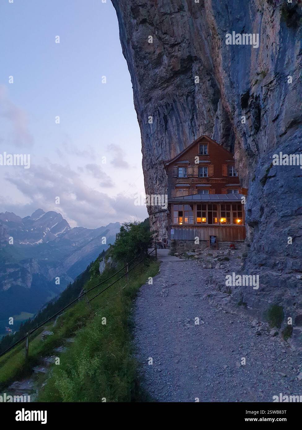 A cozy wooden cabin nestled beneath a towering cliff in the Swiss Alps ...