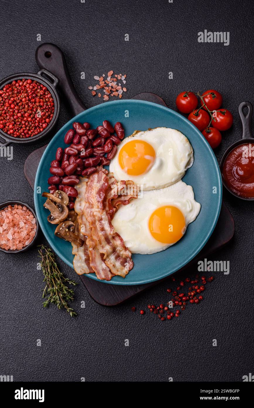 English breakfast with fried eggs, bacon, beans, tomatoes, spices and ...