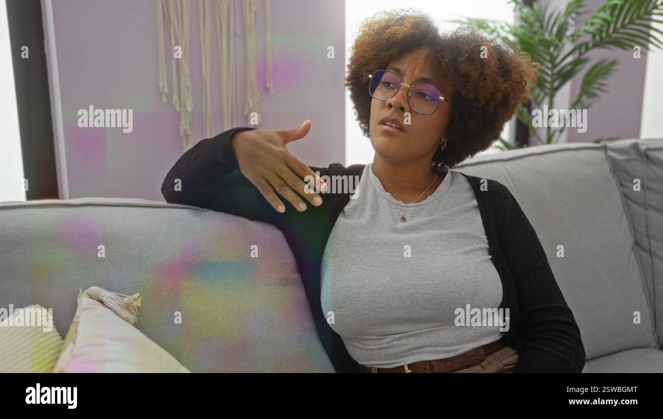 Woman with curly hair sitting on a sofa with expressive gesture in a ...