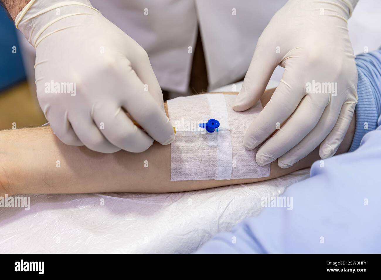 The doctor inserts a needle into the vein of the patient. Nurse connecting an IV drip. Nurse ...