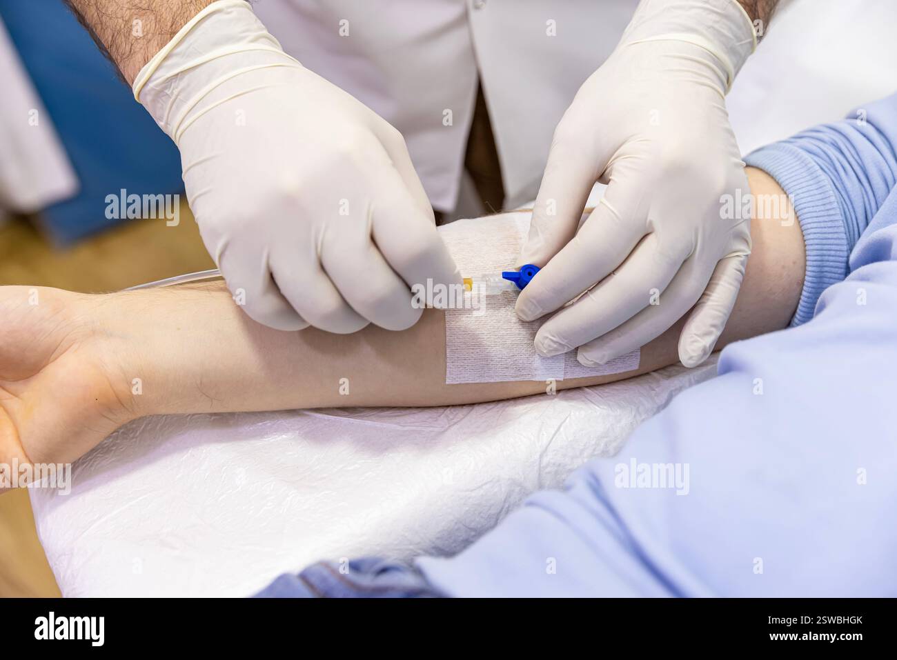 The doctor inserts a needle into the vein of the patient. Nurse connecting an IV drip. Nurse ...