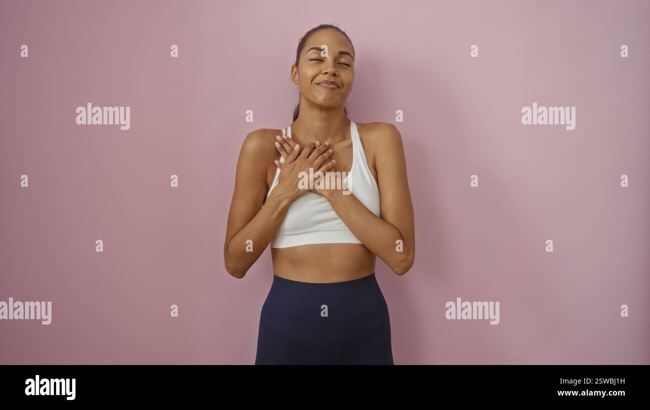 Beautiful young woman standing over pink background with a contented ...