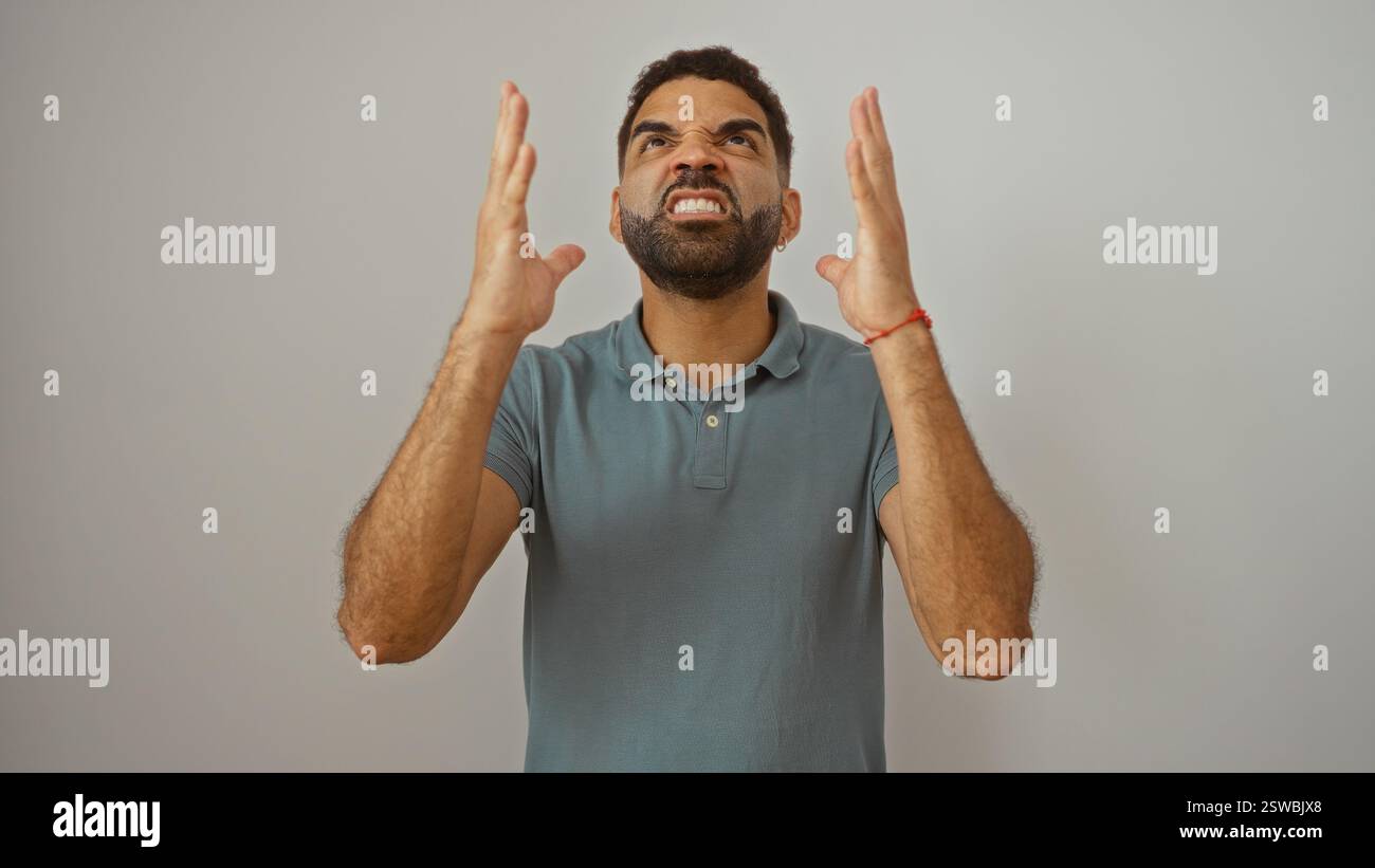 Frustrated man looking up with hands raised against white background ...