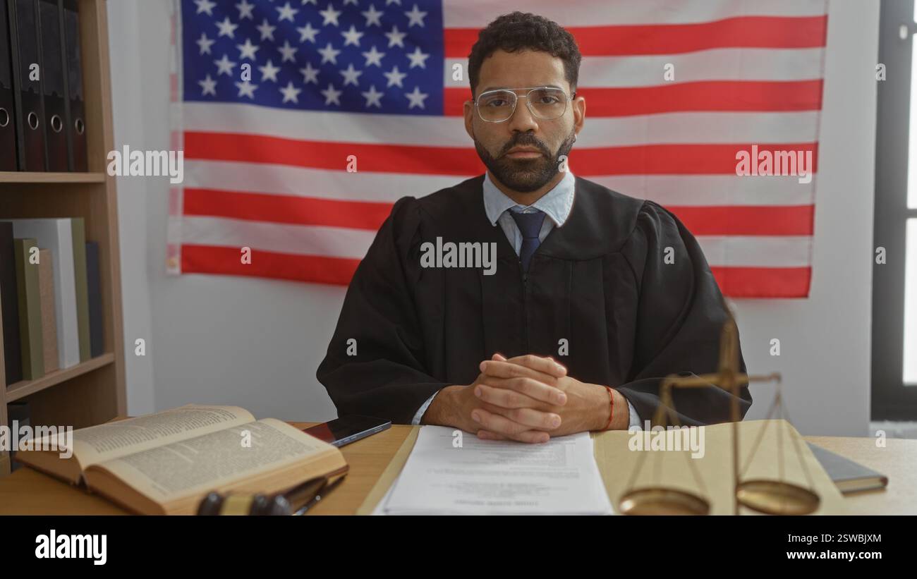 Serious young hispanic judge sitting in a courtroom with folded hands ...