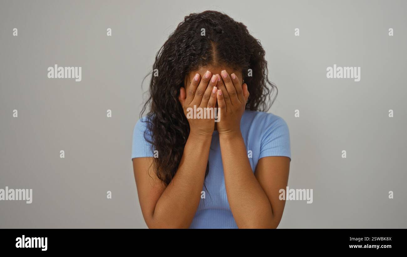 Woman covering face with hands standing over isolated white background ...