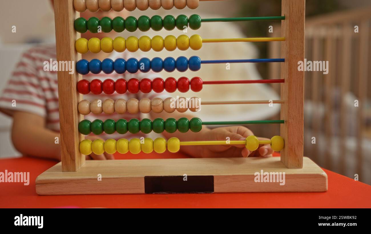 Boy using abacus in indoor kindergarten setting with colorful beads ...