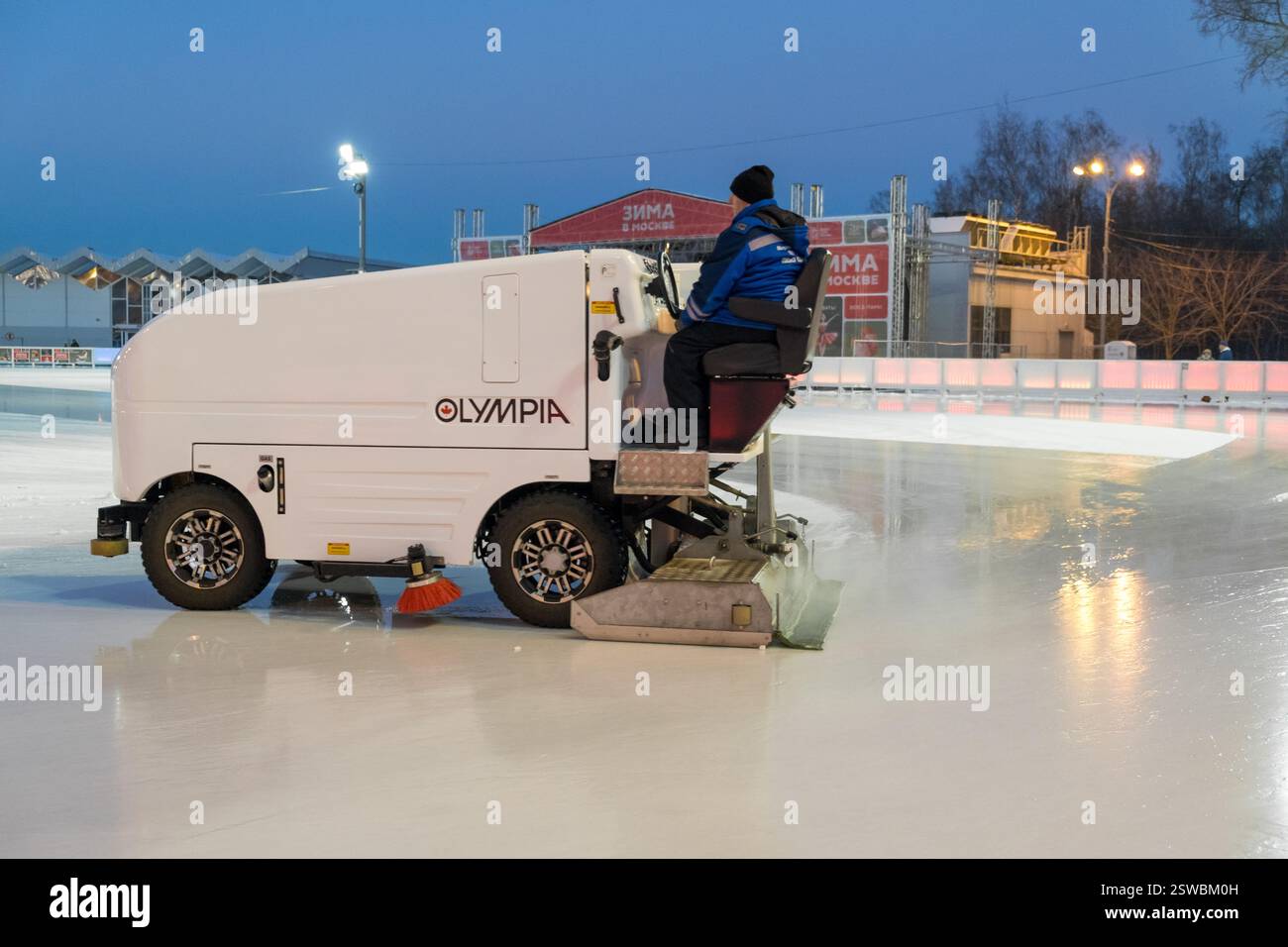 Skate rink ice cleaner working on resurfacing the rink during evening ...
