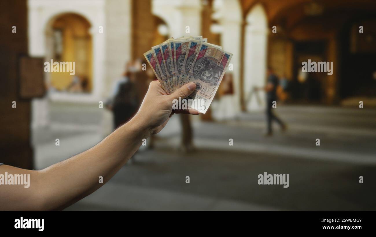 Man holding polish zloty banknotes in hand outside an old university ...