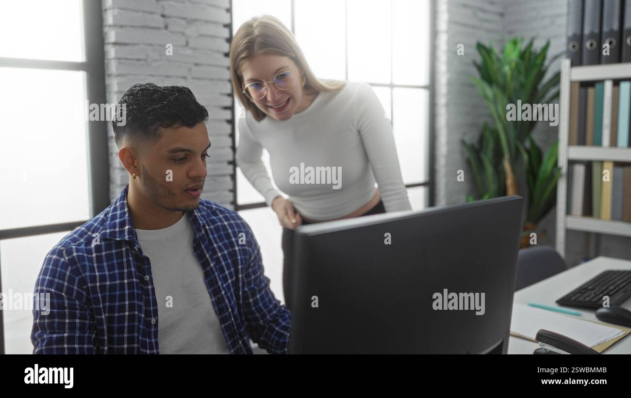 Woman assisting man at computer in modern office with plants, shelves ...
