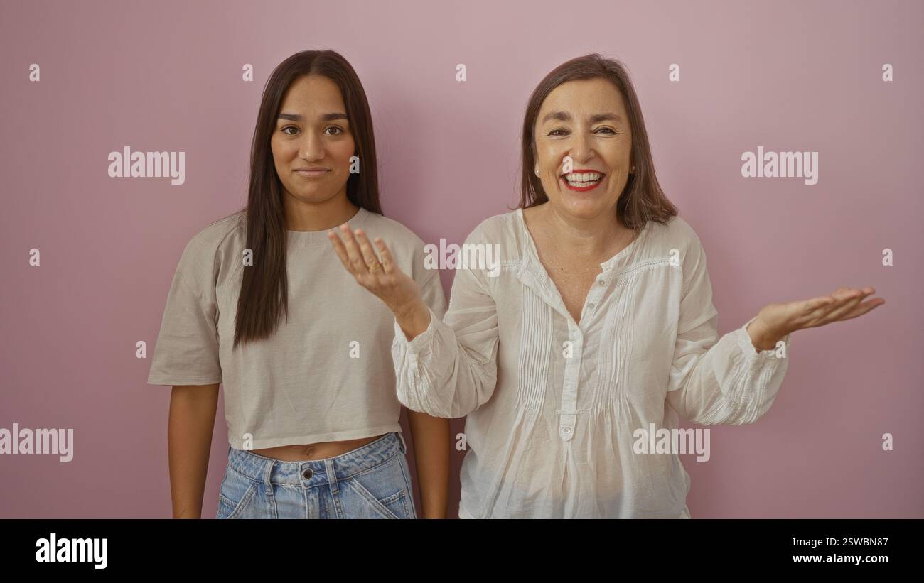 Mother and daughter standing together against a pink background, both ...