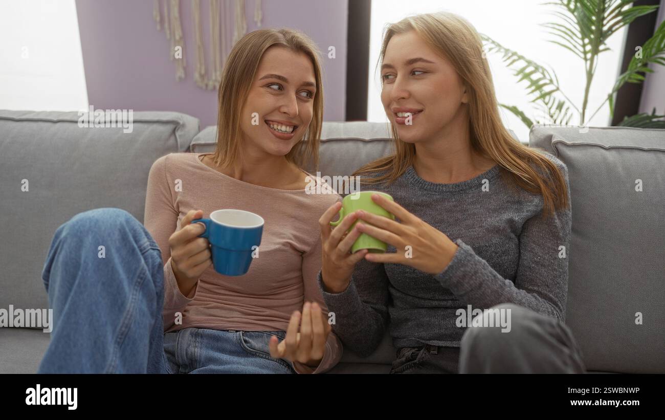 Sisters sitting together in a cozy living room sharing laughter and ...
