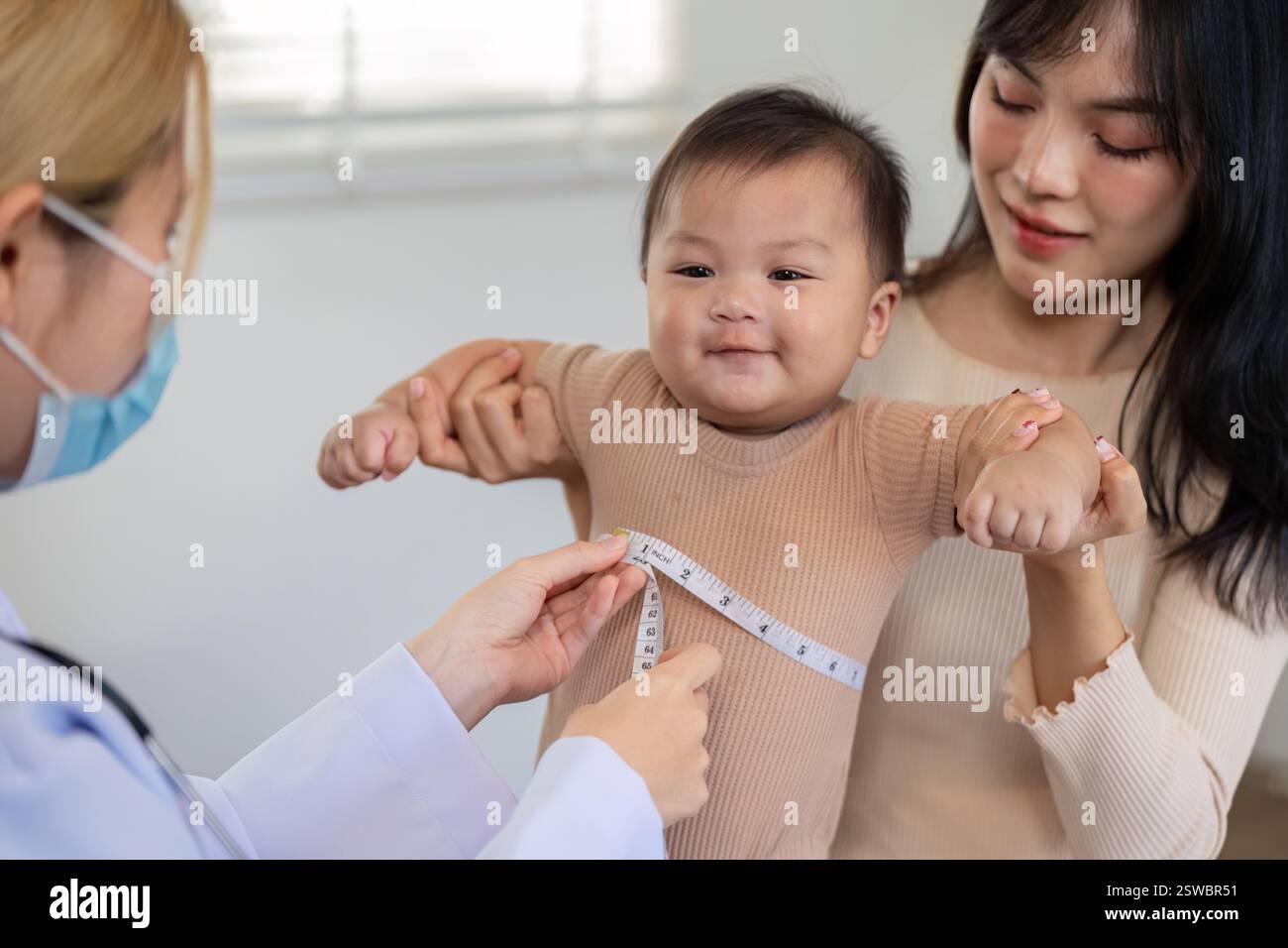 Pediatric doctor measuring baby height while parent holds child in ...