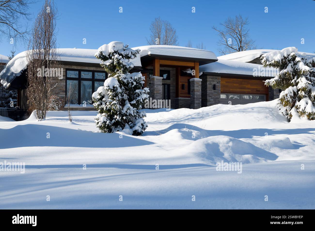 Modern house with evergreen trees buried in snow after intense ...
