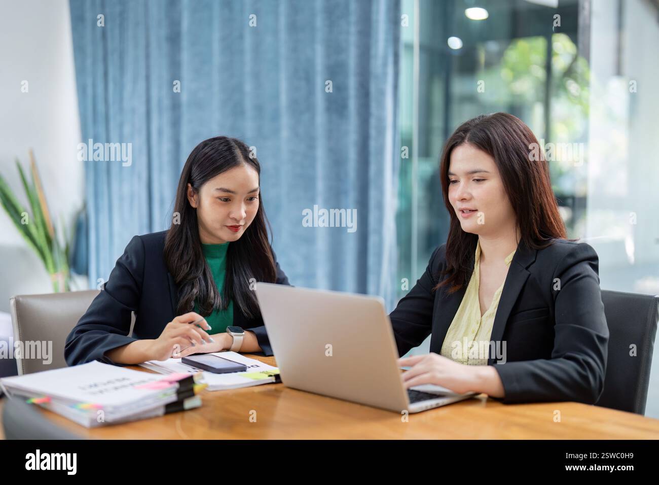 Professional women utilizing digital devices for project analysis and ...