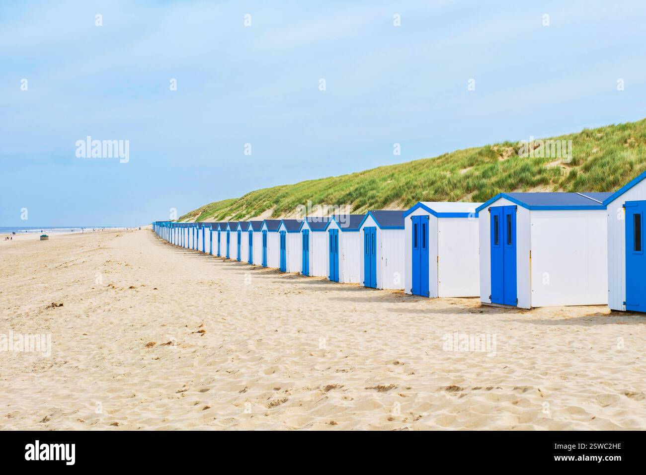Four colorful beach huts stand in a row on the sandy shore of Texel ...