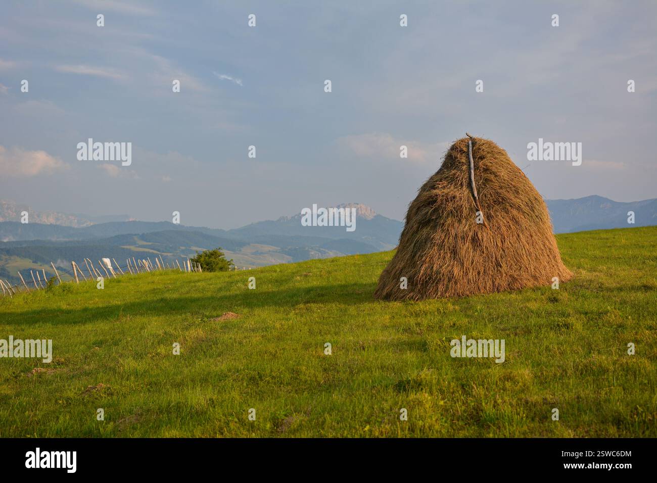 Rural landscape featuring a haystack rolling green hills and distant ...