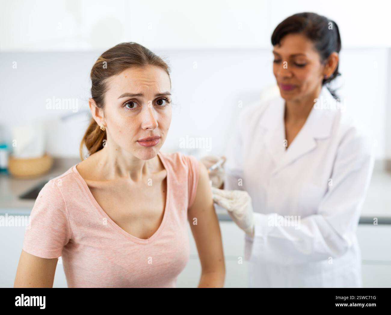Scared woman getting injection at doctors office Stock Photo - Alamy