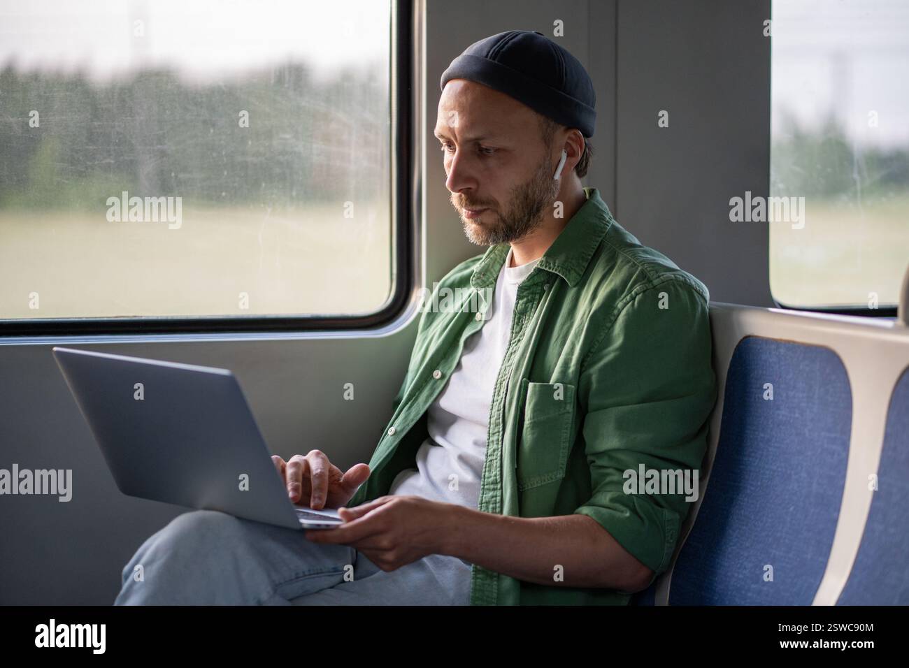 Focused tech savvy businessman type on laptop, wearing earphones while ...