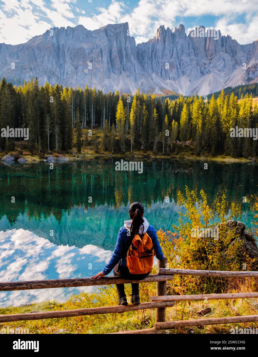 A traveler at the edge of a sparkling lake nestled in the Dolomites ...